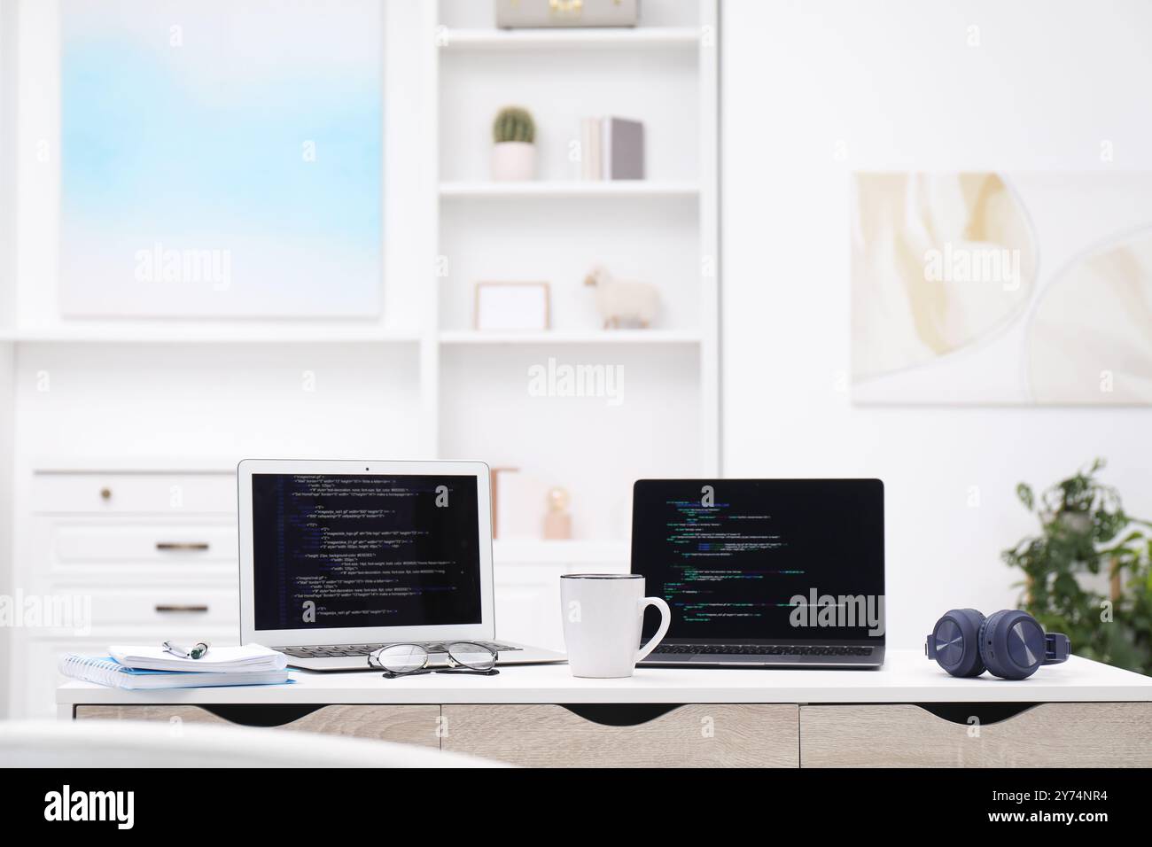 Programmer's workplace. Modern laptops with unfinished code, cup and ...