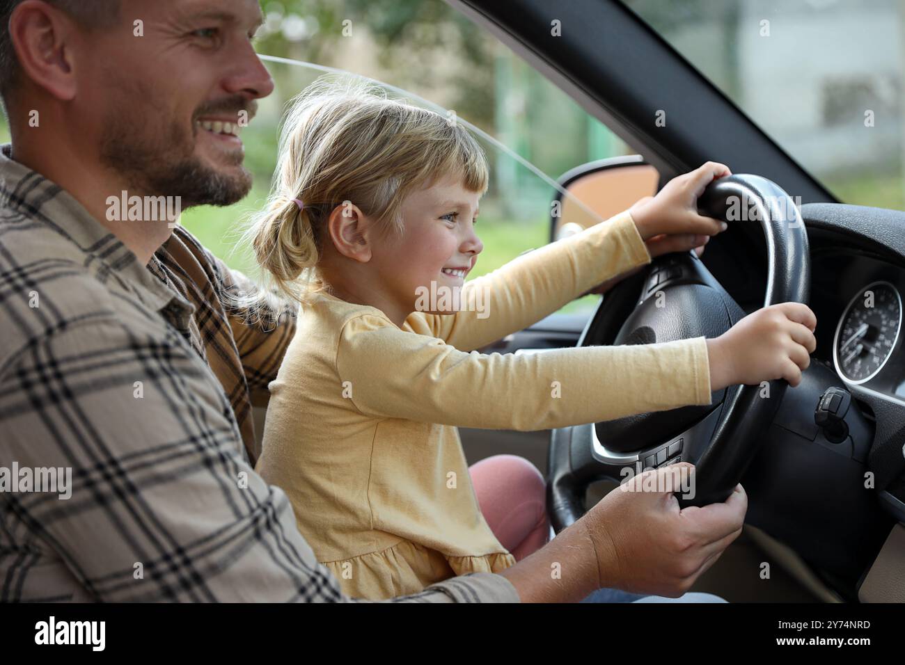 Happy man with his daughter holding steering wheel inside car Stock ...