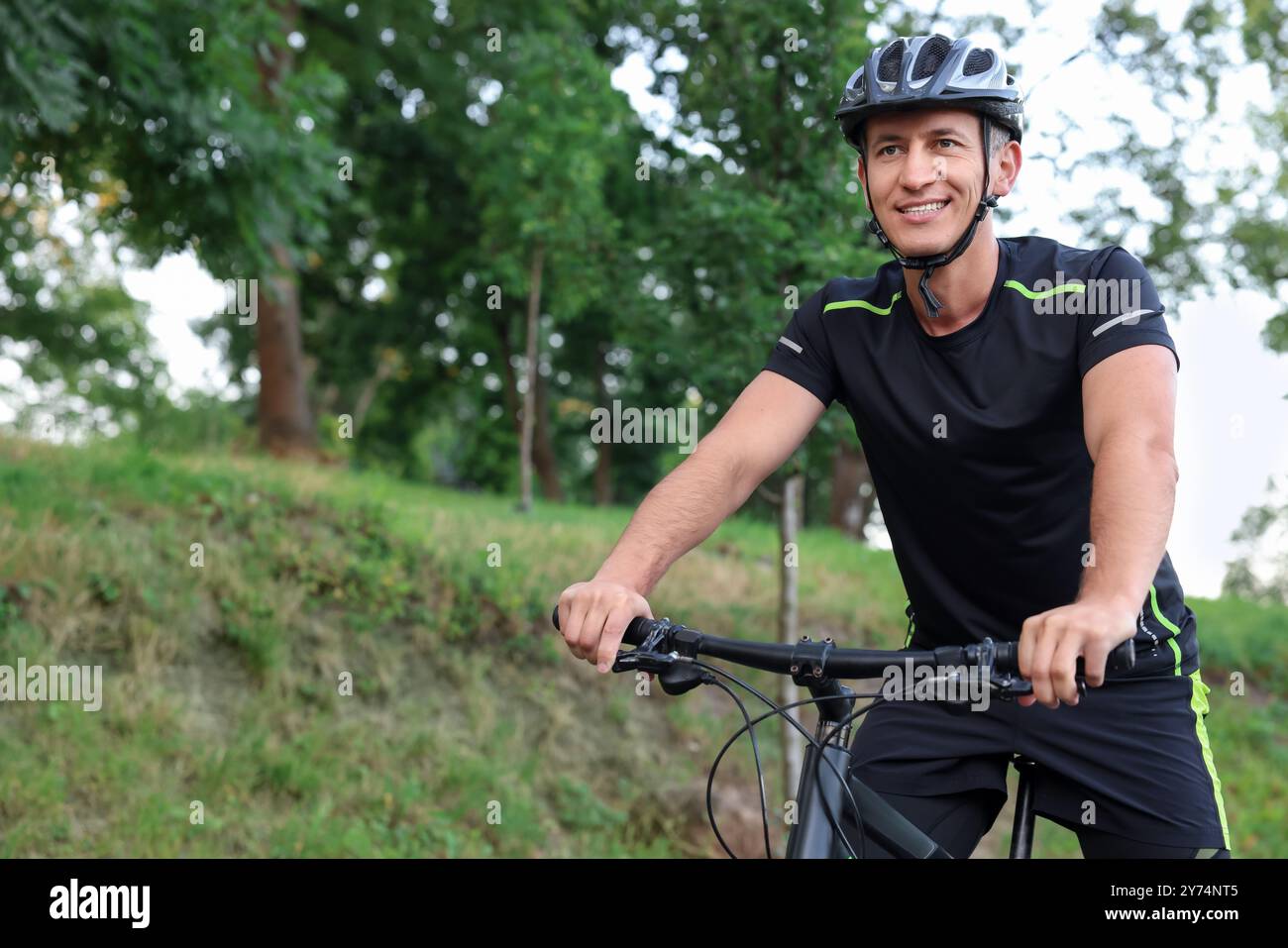 Happy man riding bicycle in park, space for text. Healthy lifestyle ...