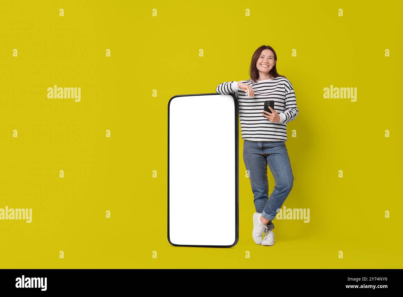 Happy smiling woman with smartphone standing near big mobile phone with ...