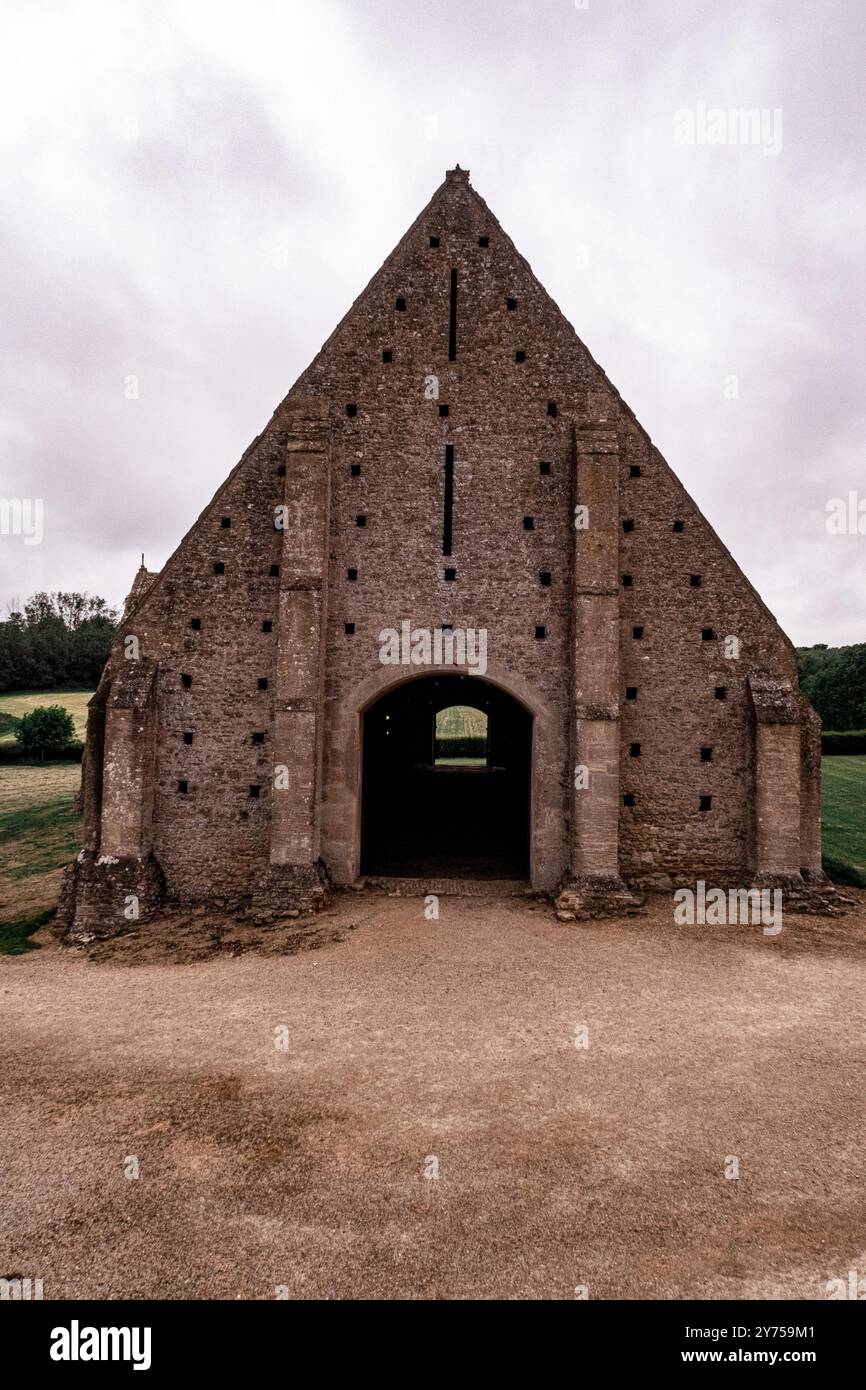 A historic stone barn with a triangular roof and arched entrance in a ...