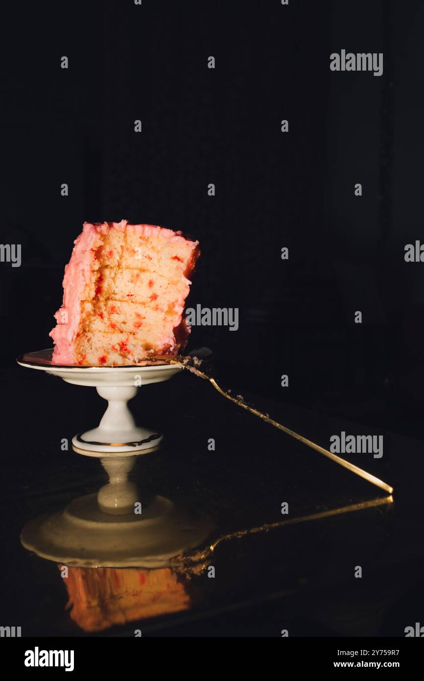 a single brass fork digging into a tall personal confetti white cake ...