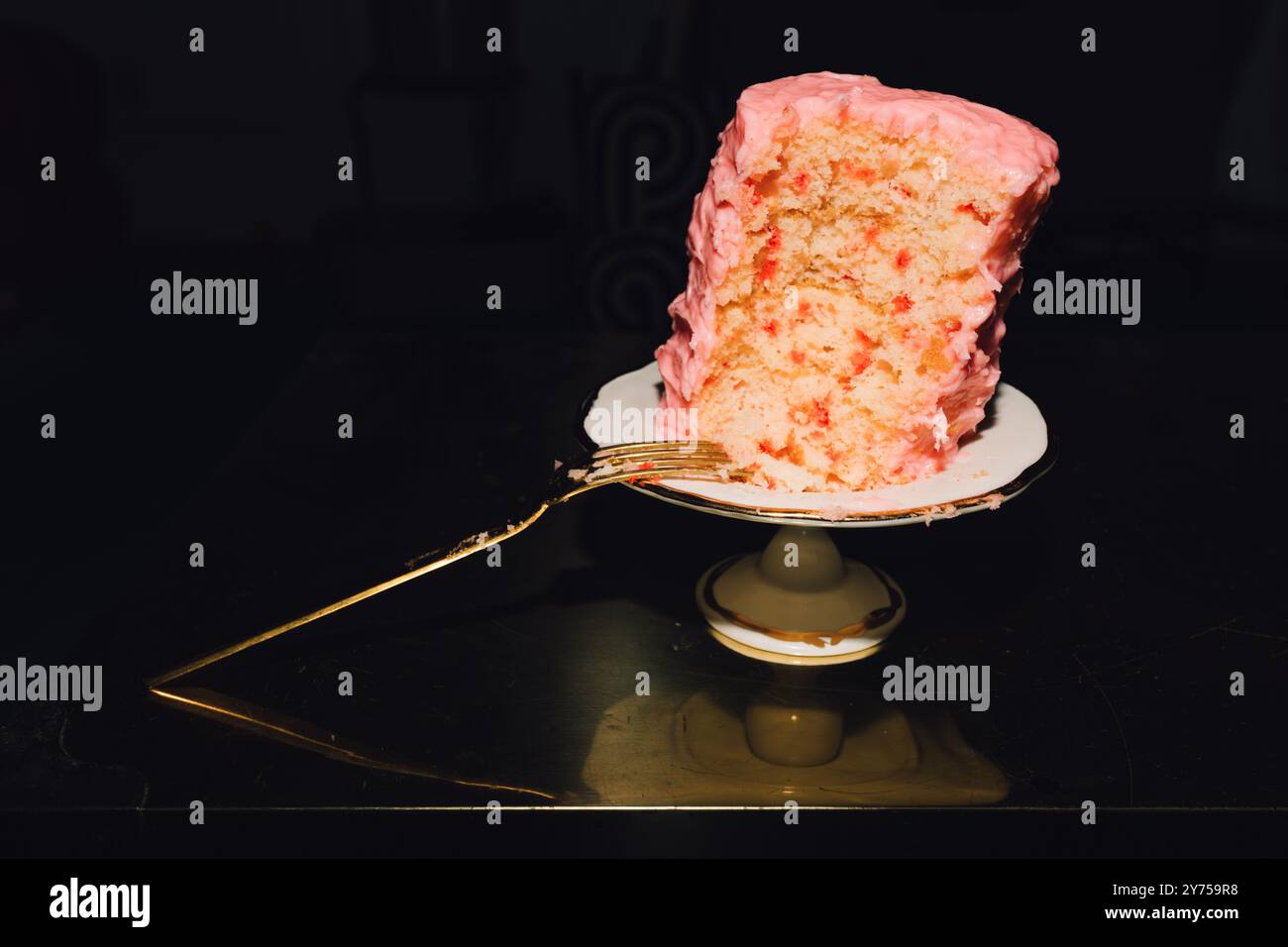 a single brass fork digging into a tall personal confetti white cake ...