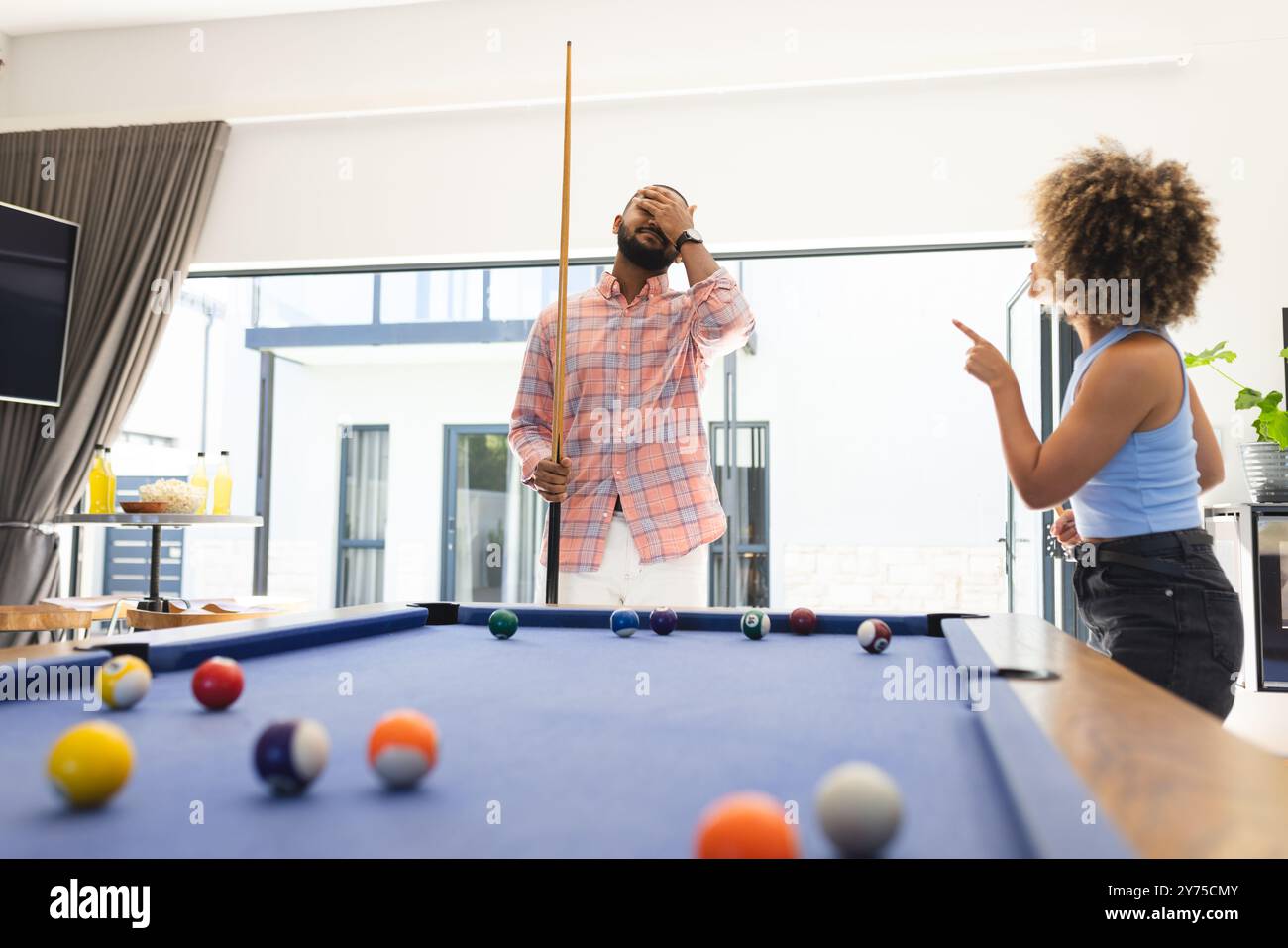 Playing pool, man covering face while woman pointing and laughing, at ...
