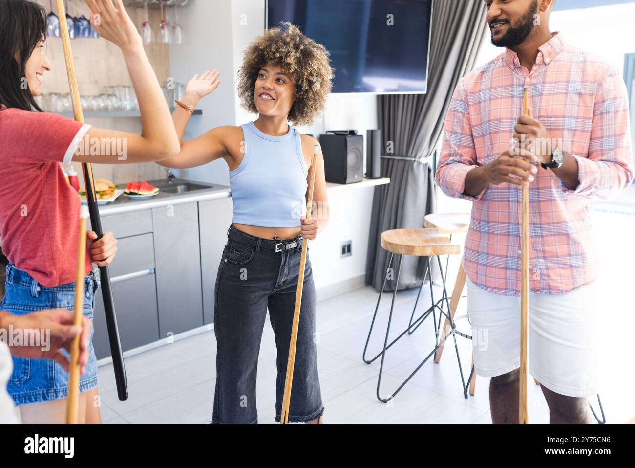 Playing pool, diverse friends high-fiving and enjoying social time ...