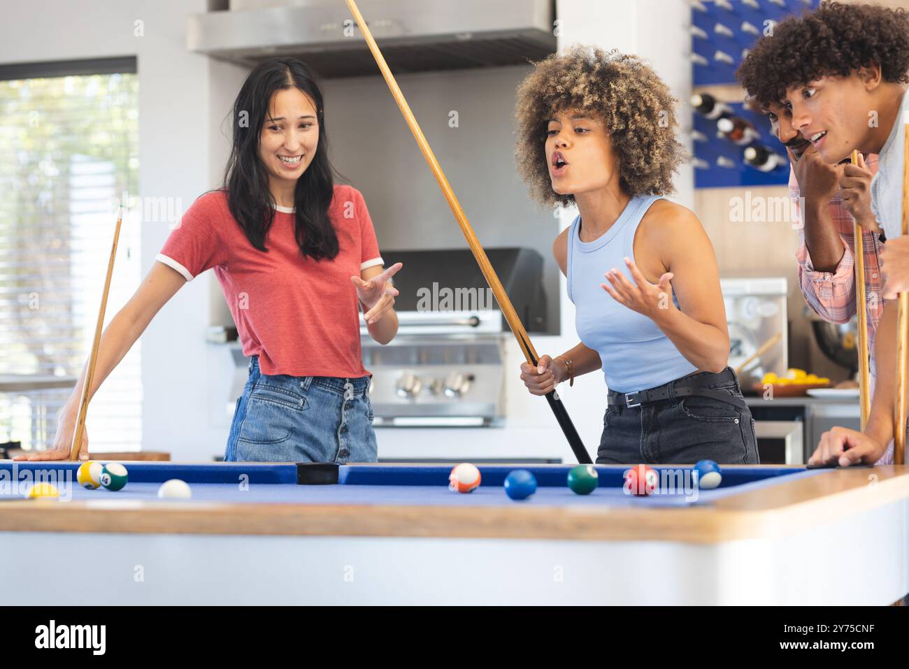 Playing pool, diverse friends enjoying fun hangout and socializing ...