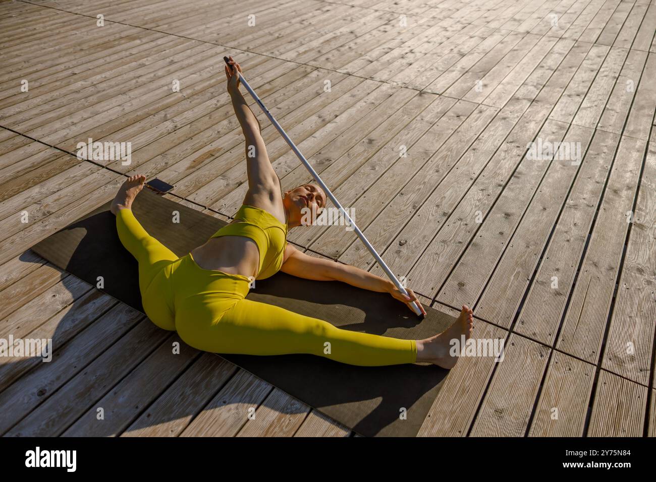 Engaging in a Flexible Yoga Pose on a Beautiful Sunrise Deck Using a ...