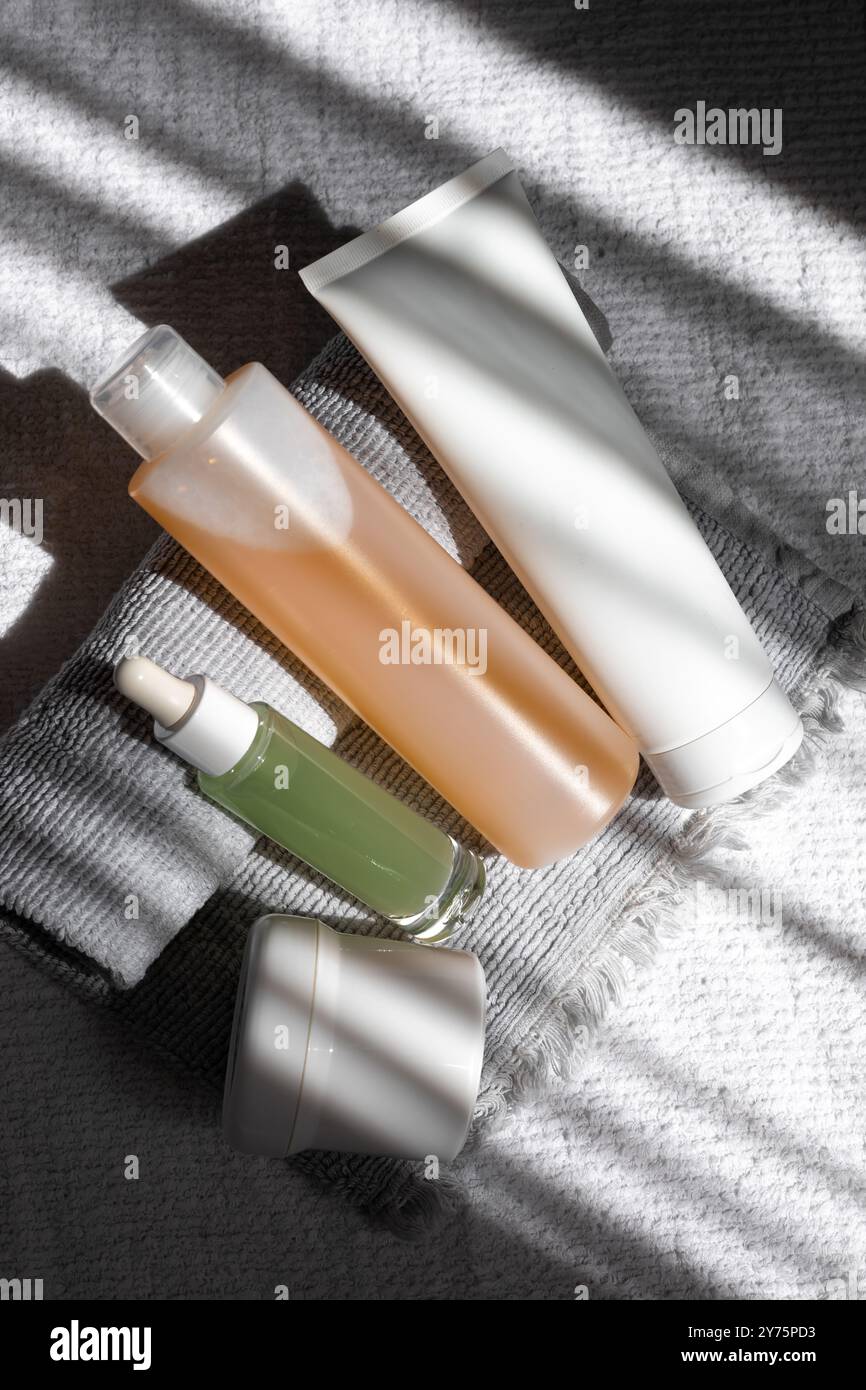 Skincare products arranged on a textured surface with natural light ...