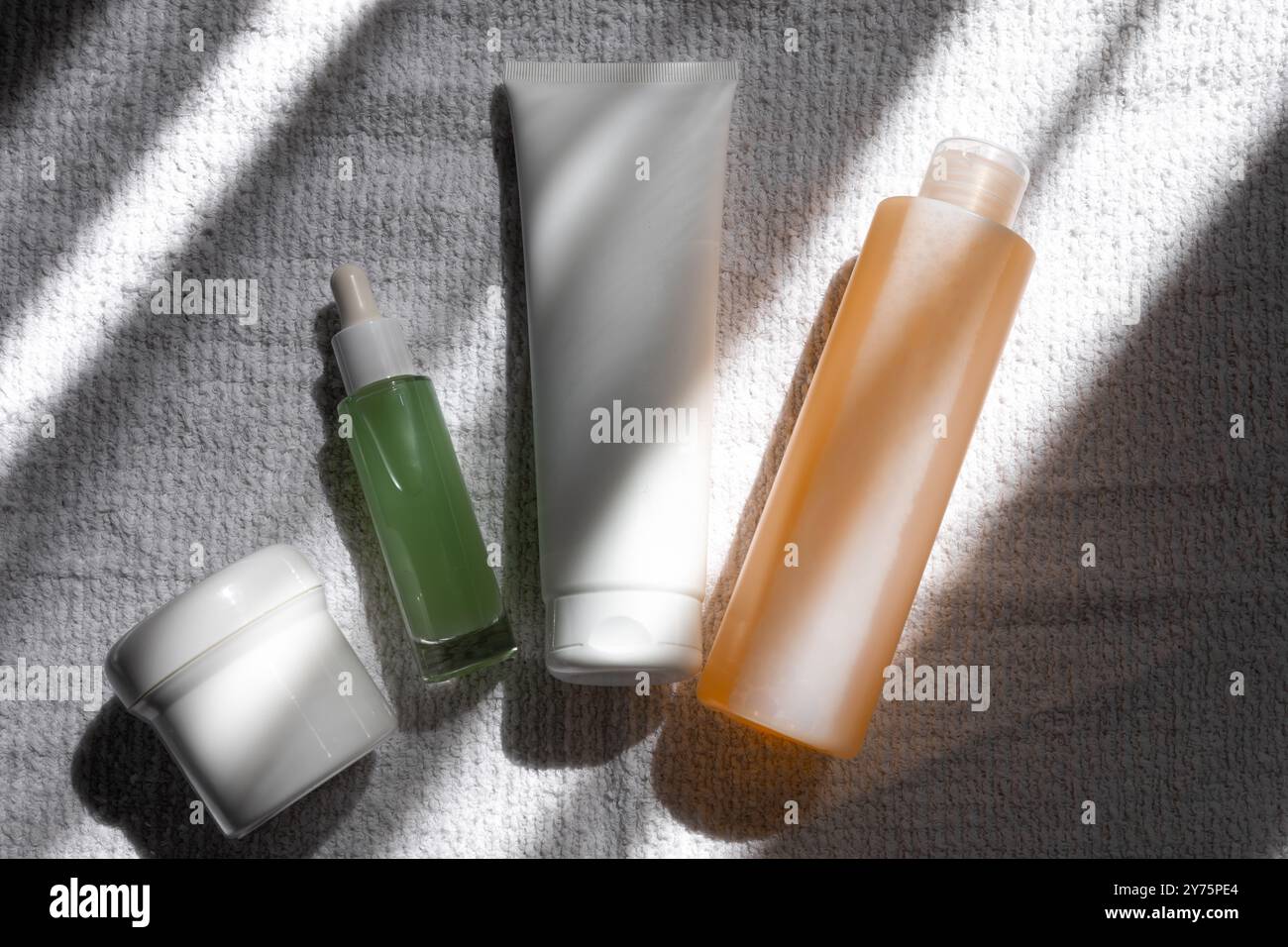 Skincare products arranged on a textured surface with natural light ...
