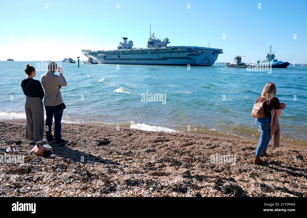 People look out from Hotwalls beach as the Royal Navy aircraft carrier ...