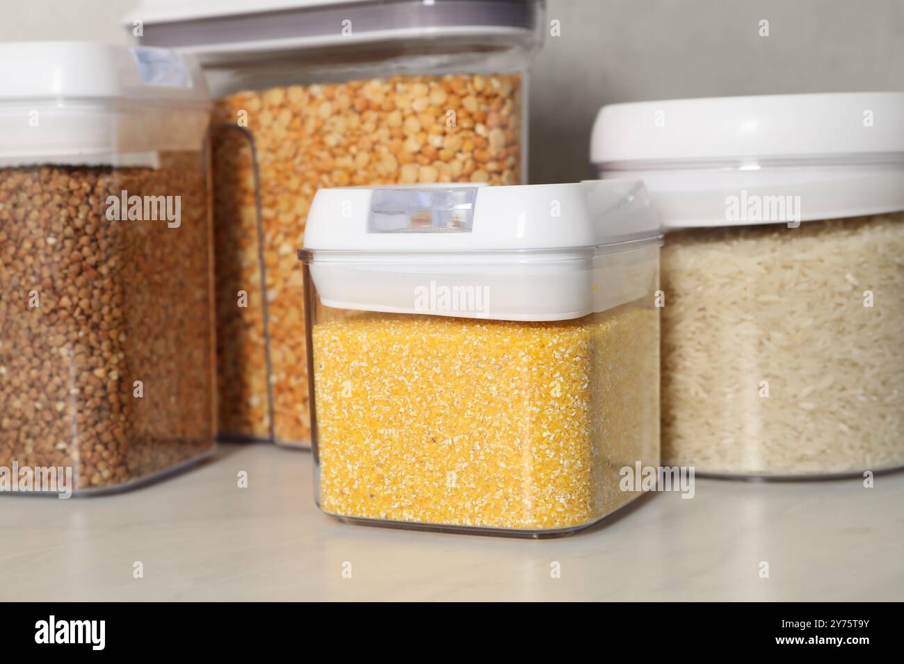 Different types of cereals in containers on light marble table, closeup ...