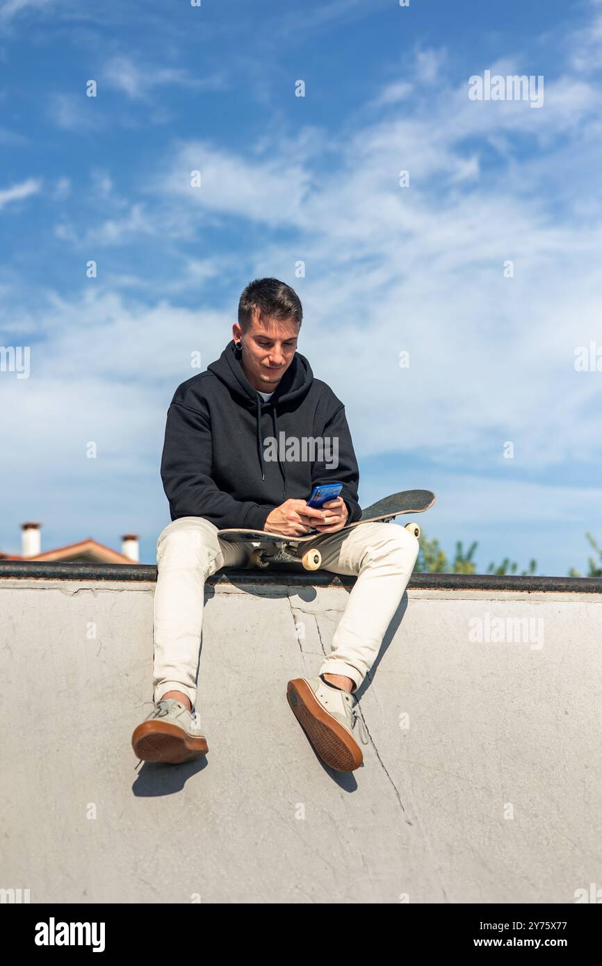 vertical skater comfortably sitting at the edge of a half-pipe, focused ...
