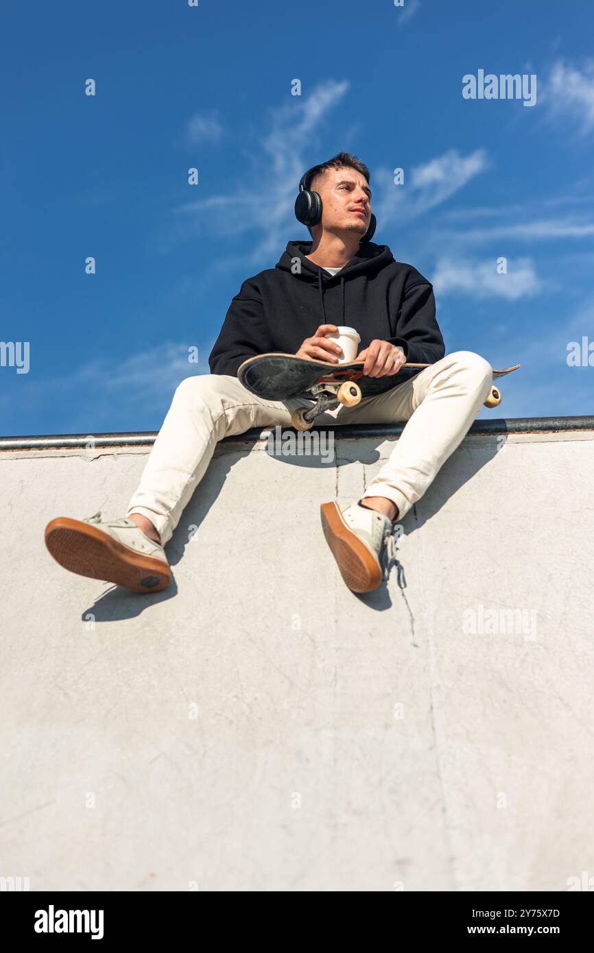 low-angle shot captures a skater seated on the edge of a half-pipe ...