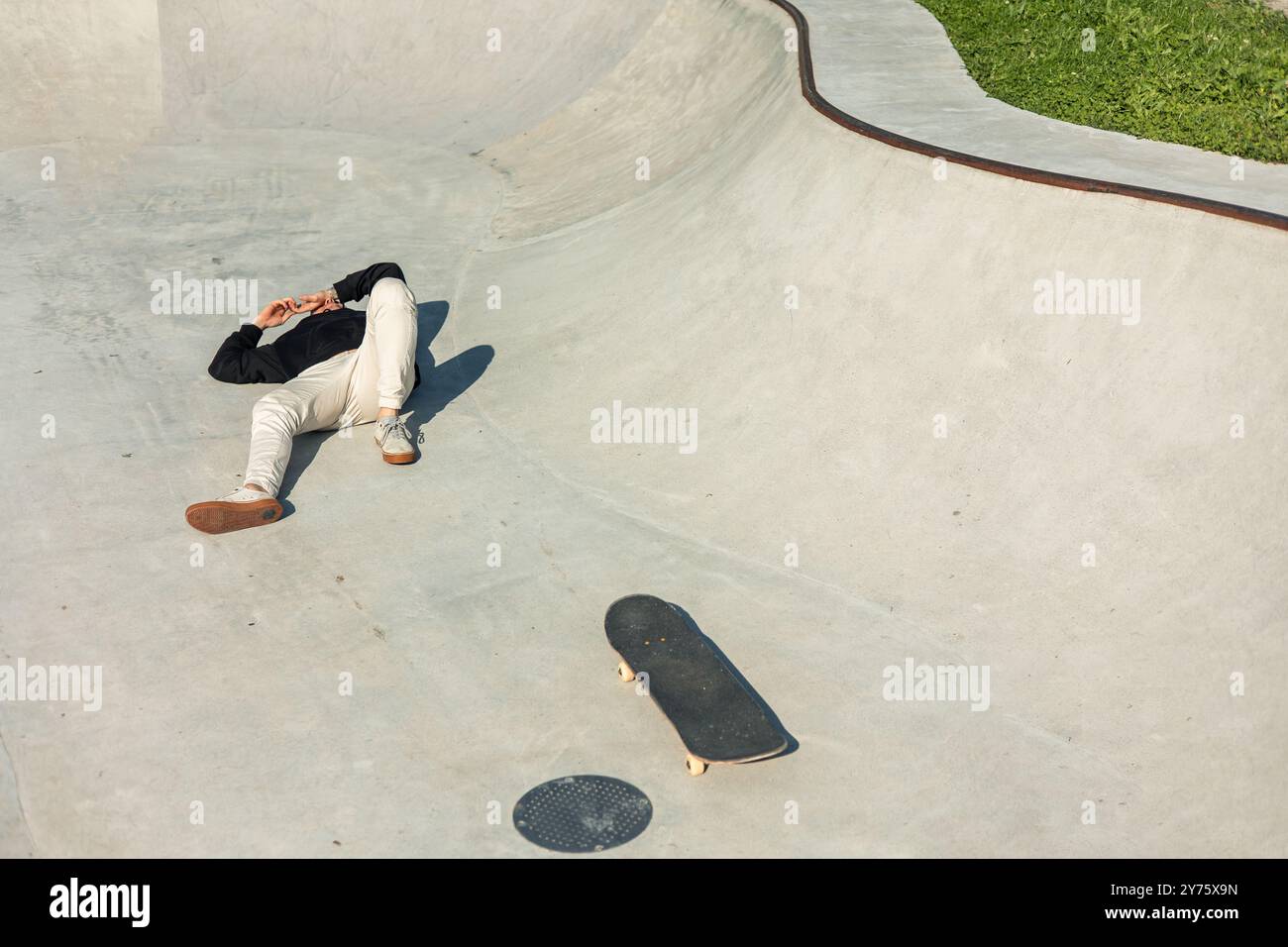 hurt skater lying on the ground at the skate park after falling from ...