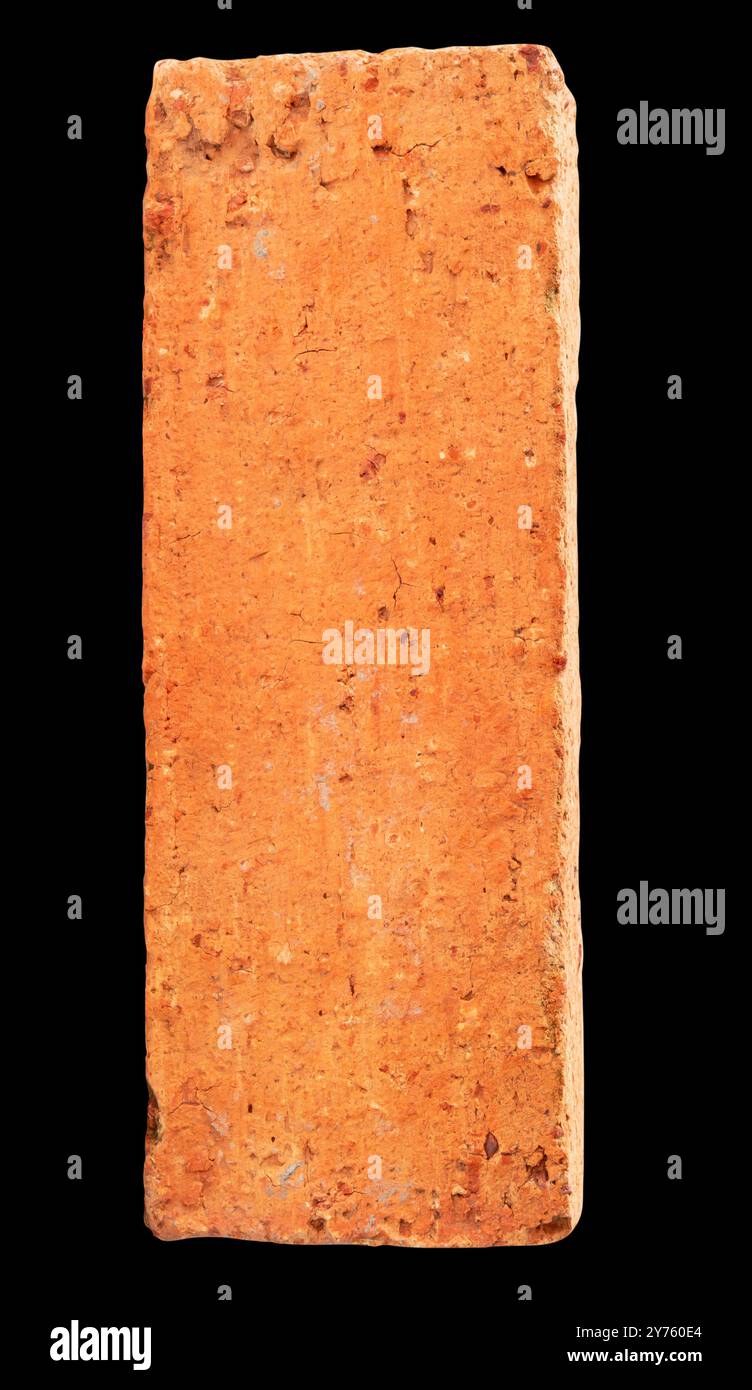 Single cracked old red or orange brick is isolated on black background ...