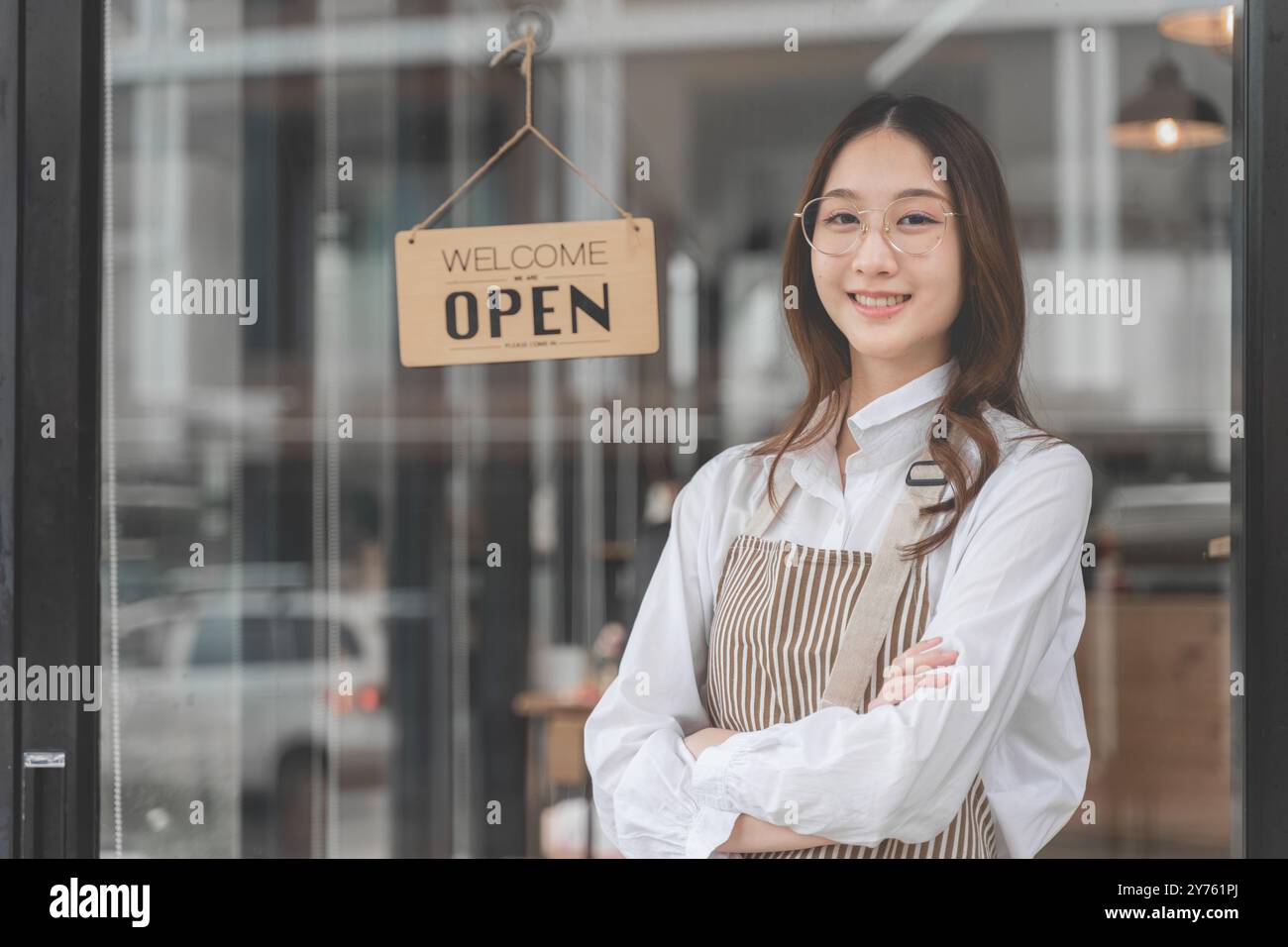 Happy proud young female coffee shop owner standing outside of her shop ...