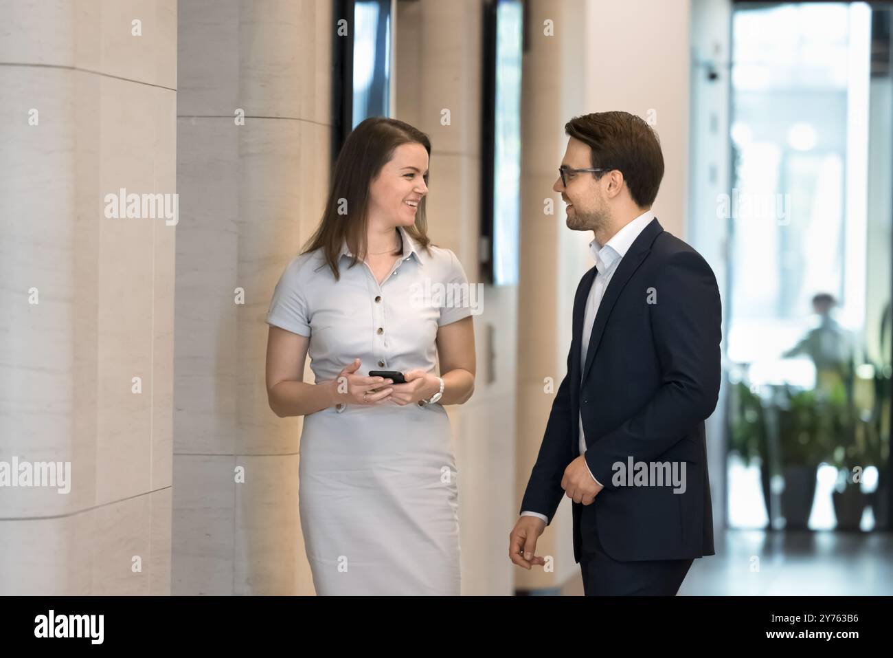 Positive couple of business colleagues talking, chatting in office ...