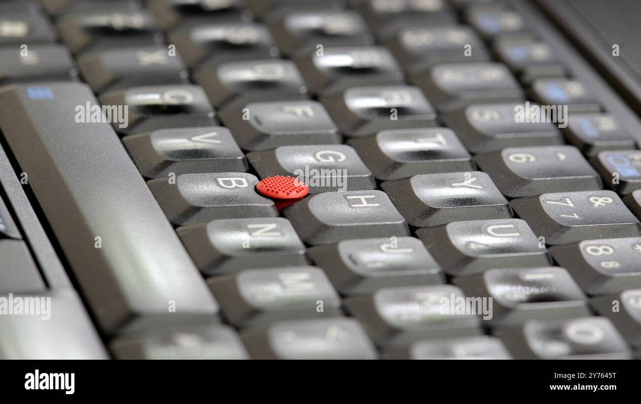 Laptop keyboard with a red track point in the middle, shallow depth of ...