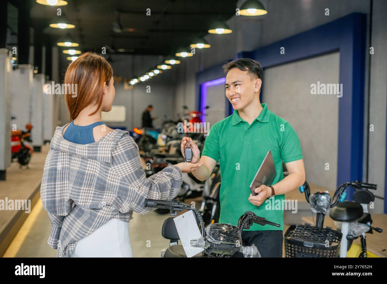 salesman giving electric bike key female customer Stock Photo - Alamy