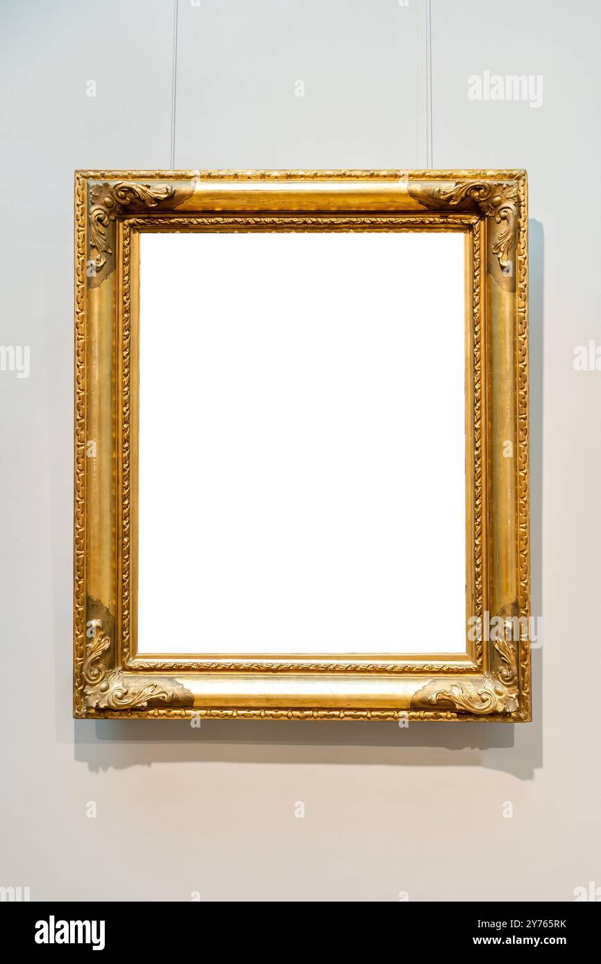 One single old gilded painting frame hanging on a white wall, blank ...