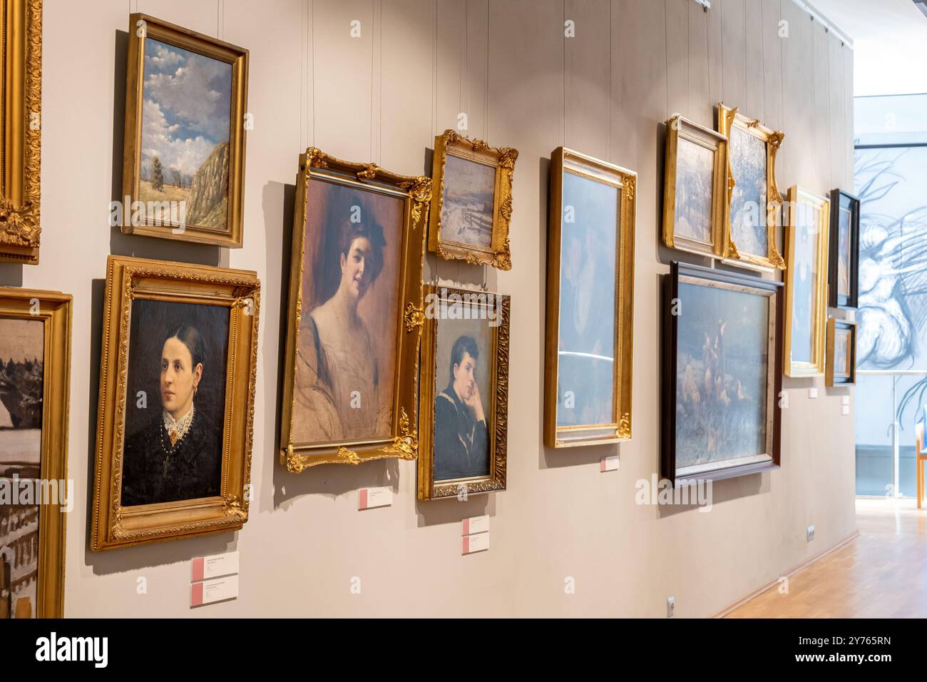 Various different paintings in gold gilded frames hanging on the wall ...