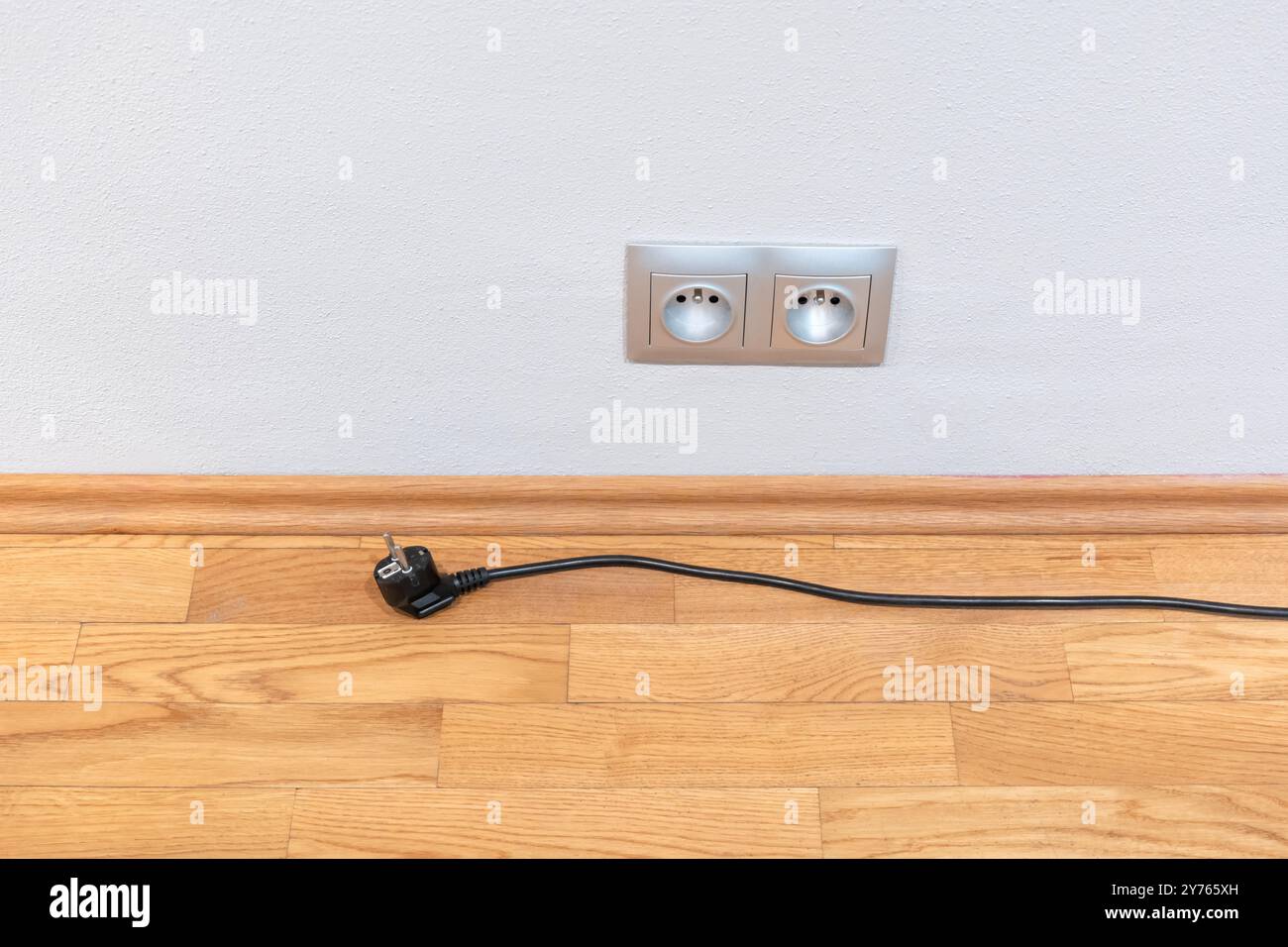 Long power cord cable European power plug laying on the floor next to ...