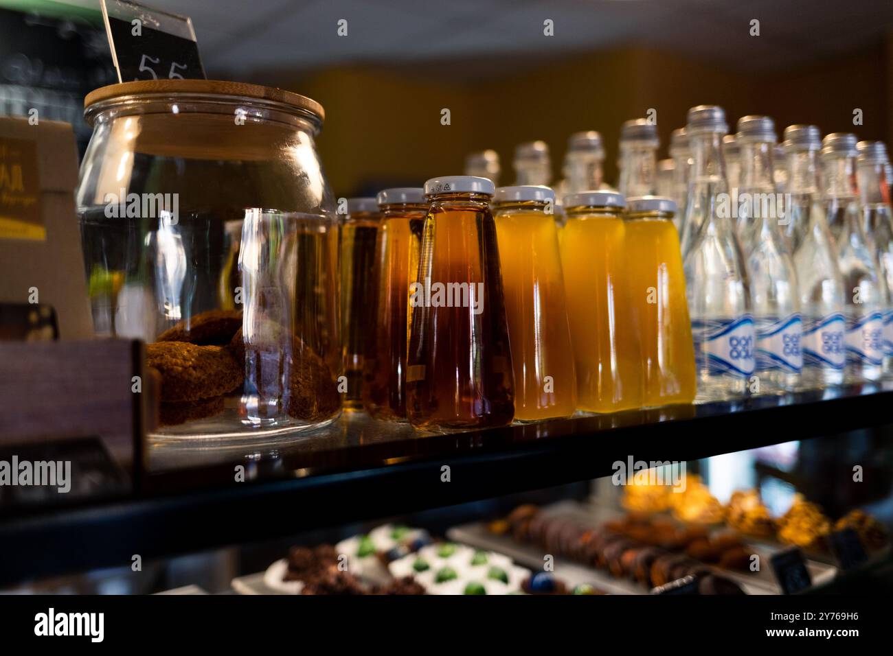 A cafe window with neatly displayed rows of glass bottles of juice and ...