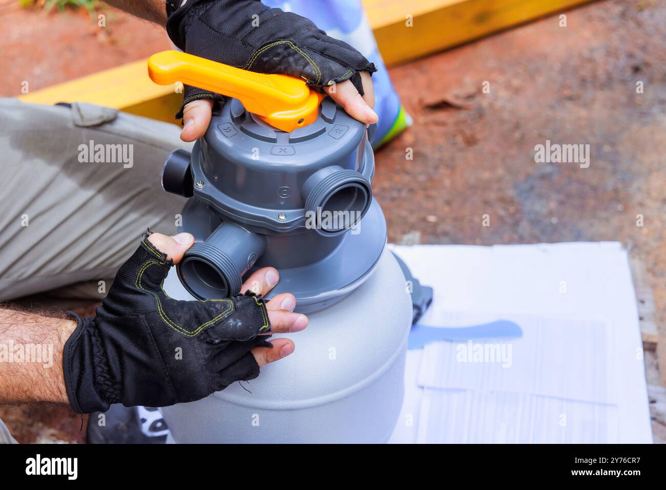 Maintenance worker assembles sand filter system tank, equipment used to ...
