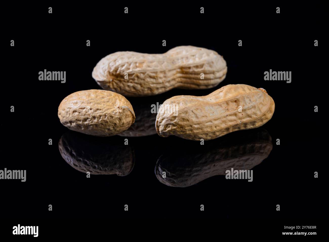 Three peanuts with black background Stock Photo - Alamy