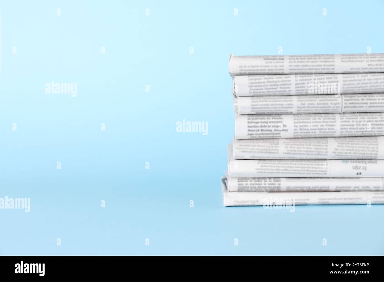 Stack of newspapers in different languages on light blue background ...