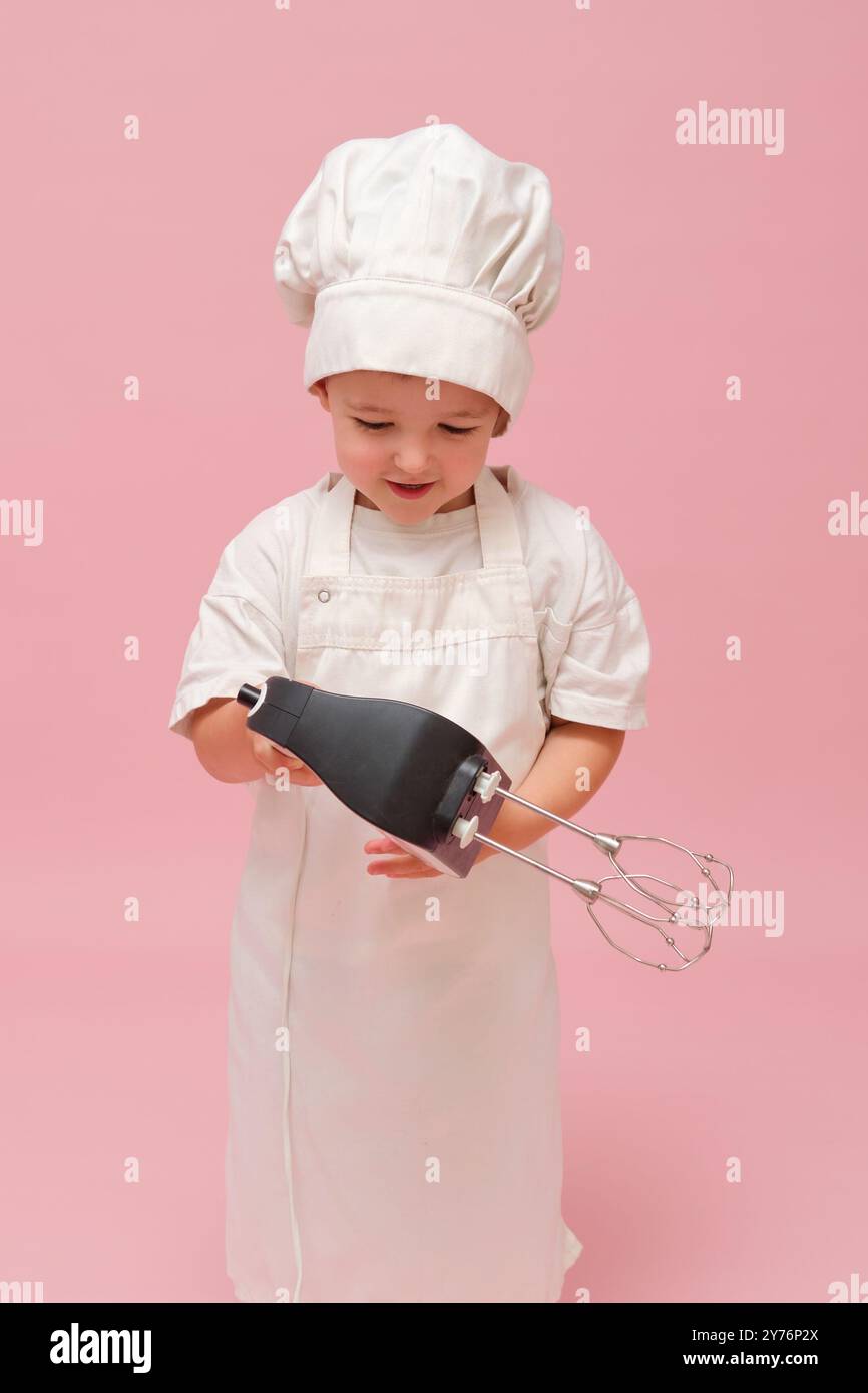 Happy baby wearing a chef's hat and apron is standing in front of a ...