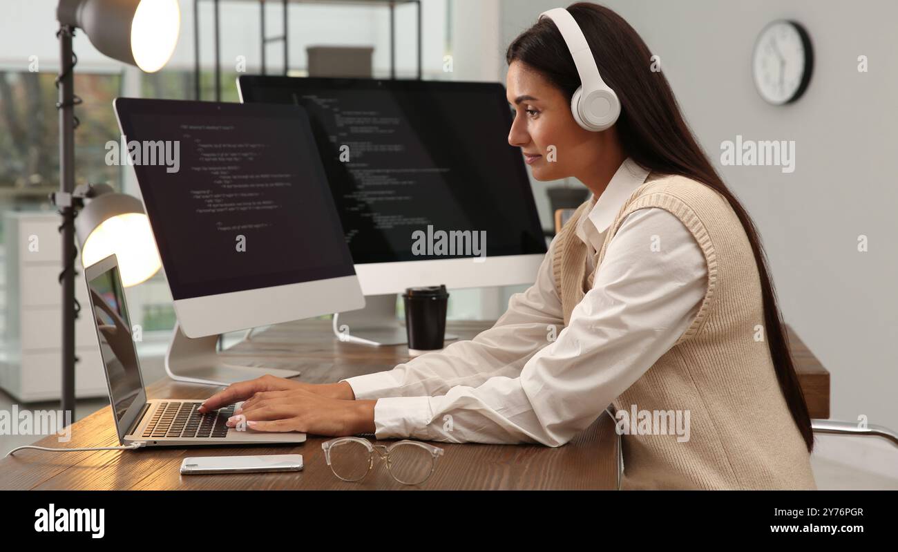 Programmer with headphones working at desk in office. Banner design ...