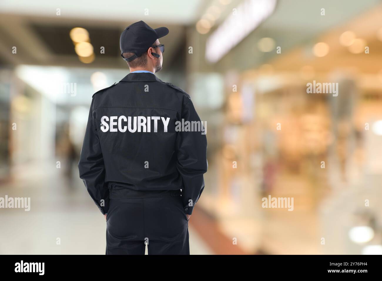 Security guard in uniform and earpiece in shopping mall, back view ...
