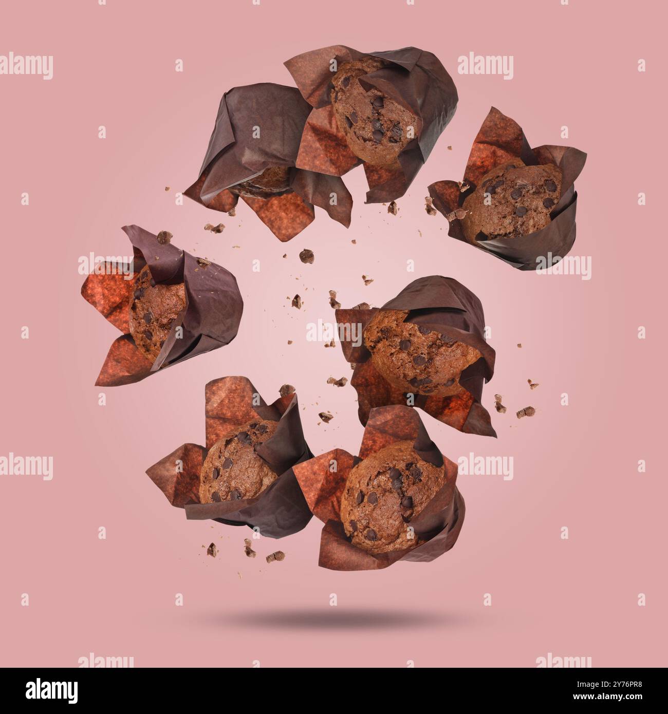 Delicious chocolate muffins and crumbs falling on pink background Stock ...