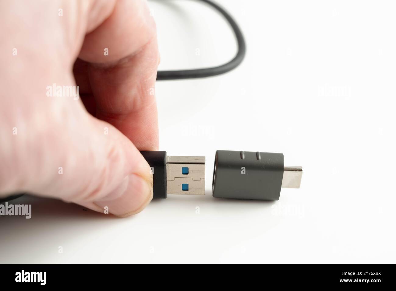 person connecting a male USB type a cable to a USB type C female ...