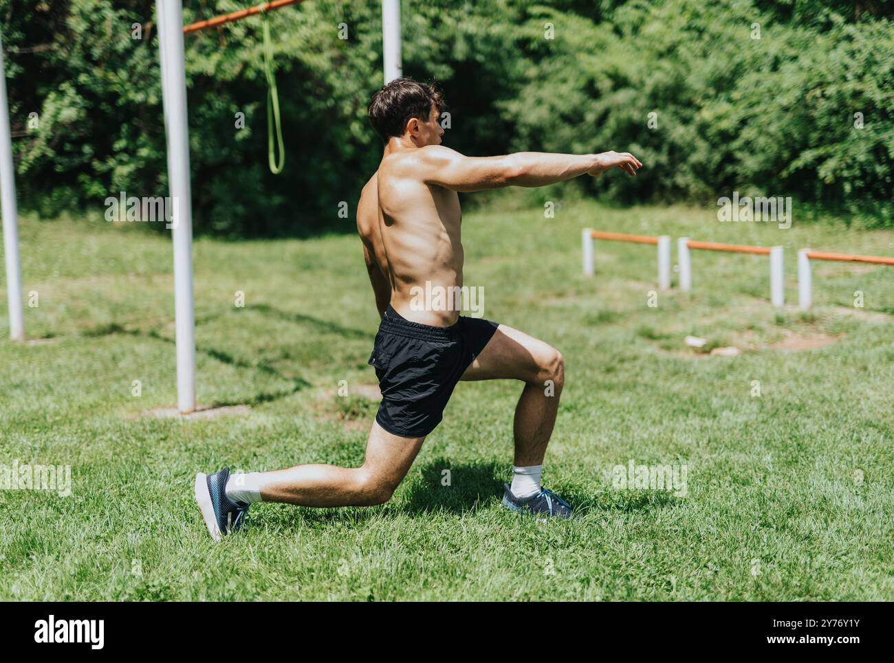 Fit male athlete performing lunges in the park for strength training ...