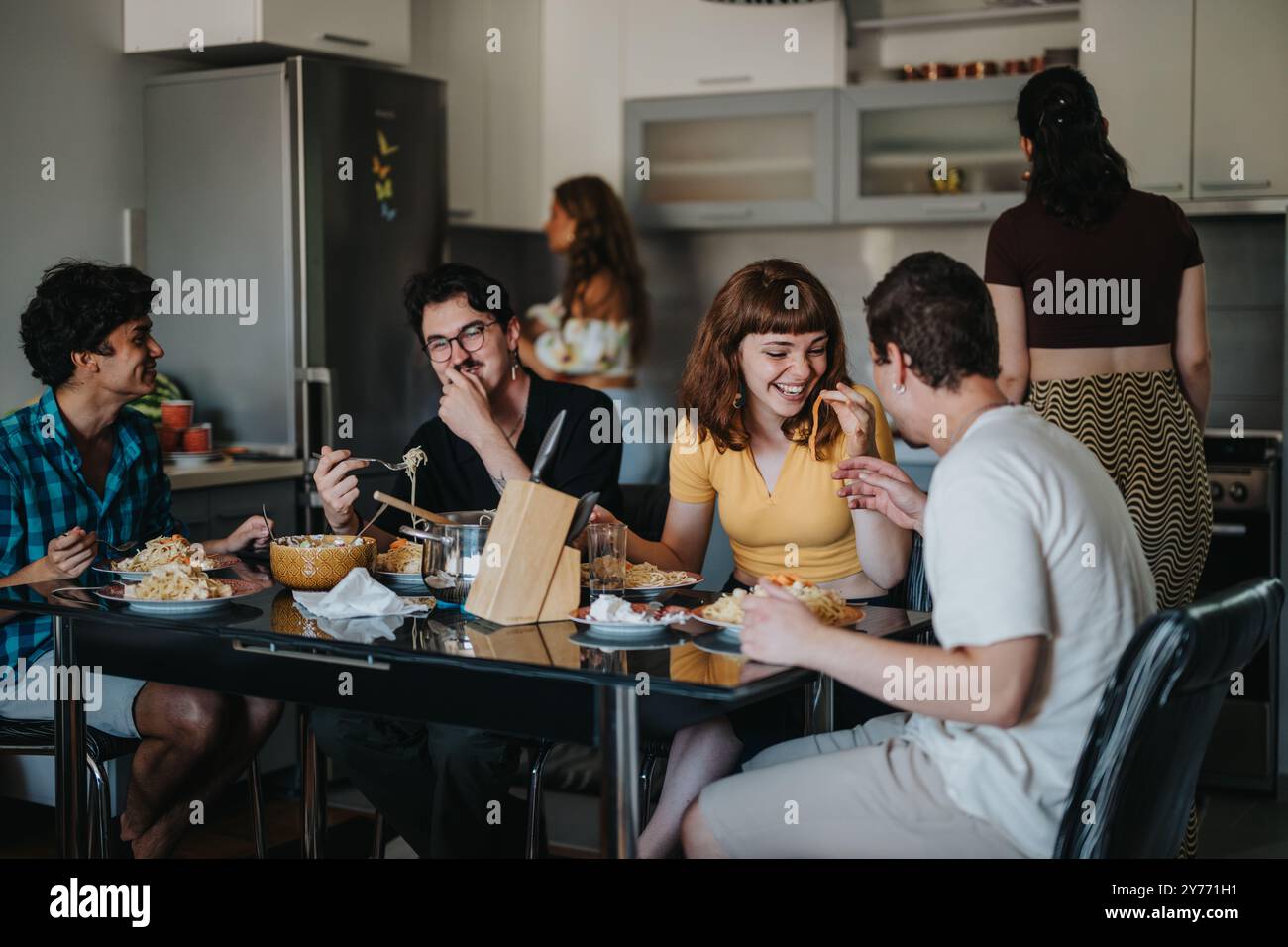 Friends enjoying a casual meal together in a modern kitchen Stock Photo ...