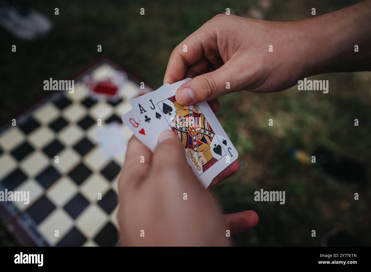 Hand holding playing cards over a chessboard during outdoor game Stock ...