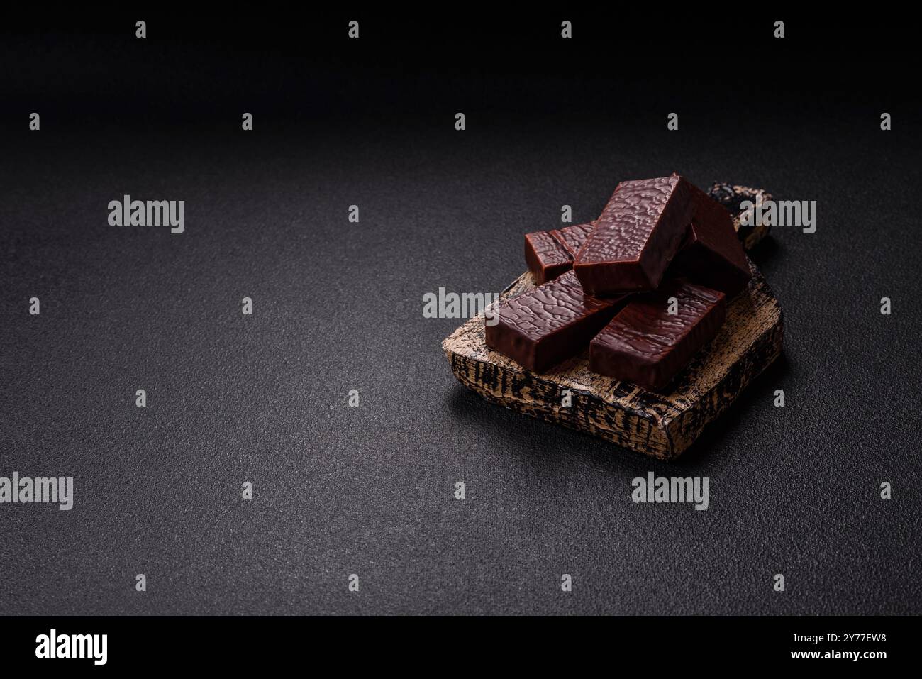 Rectangular chocolate candies with mousse and waffles on a dark ...