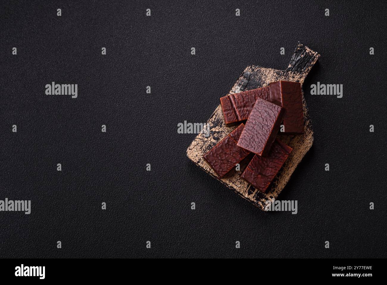 Rectangular chocolate candies with mousse and waffles on a dark ...