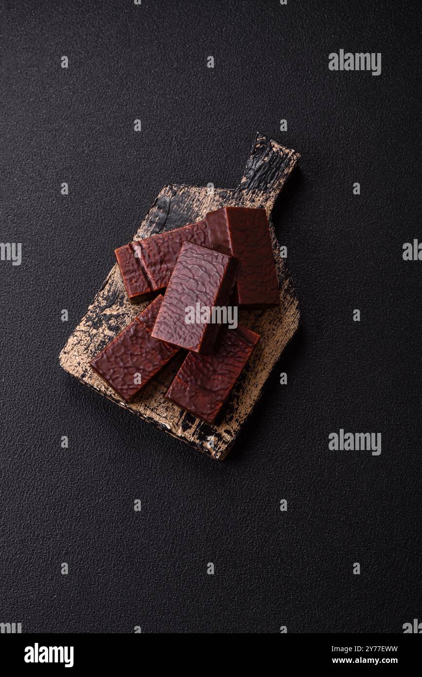 Rectangular chocolate candies with mousse and waffles on a dark ...