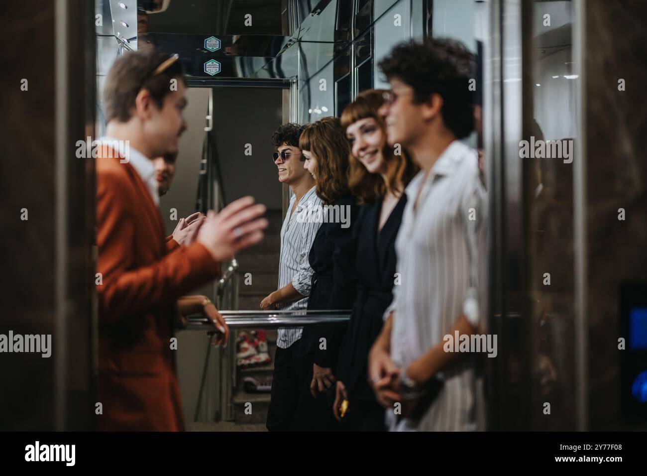 Young professionals talking and laughing in a modern elevator setting ...