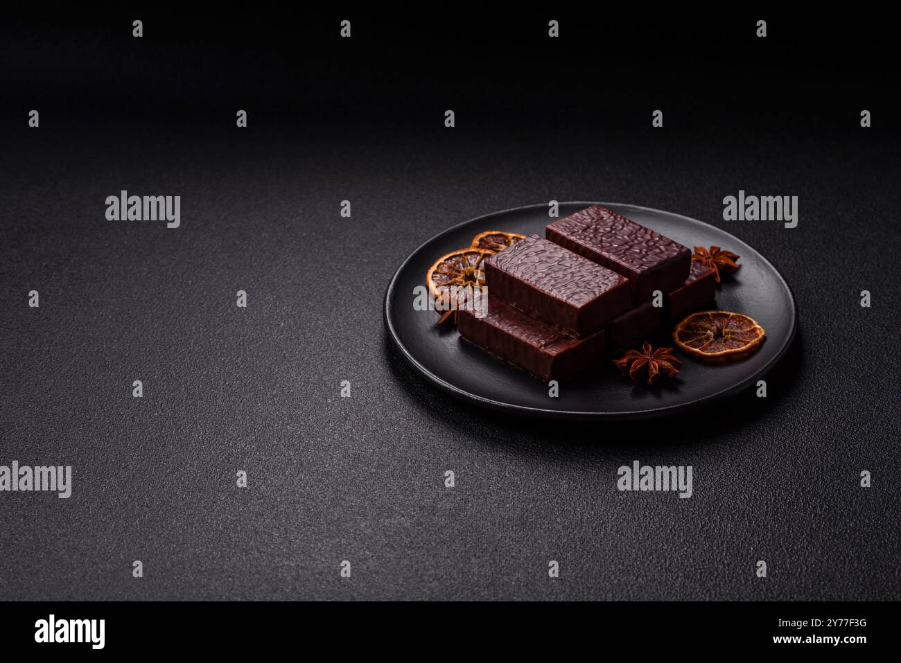 Rectangular chocolate candies with mousse and waffles on a dark ...