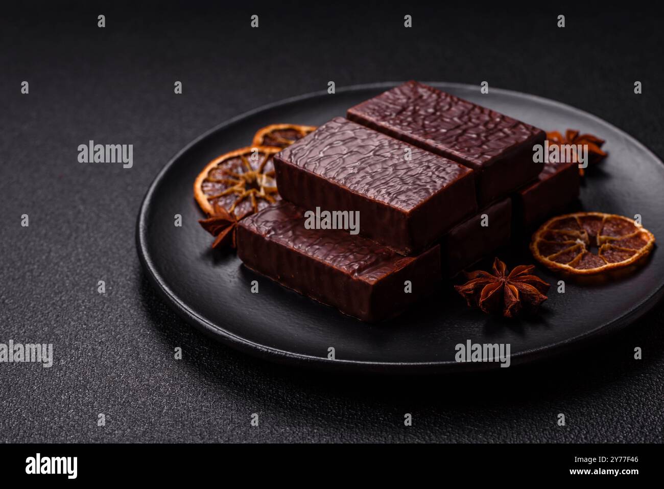 Rectangular chocolate candies with mousse and waffles on a dark ...