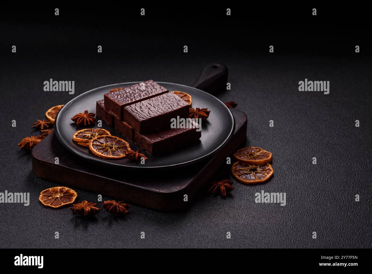 Rectangular chocolate candies with mousse and waffles on a dark ...