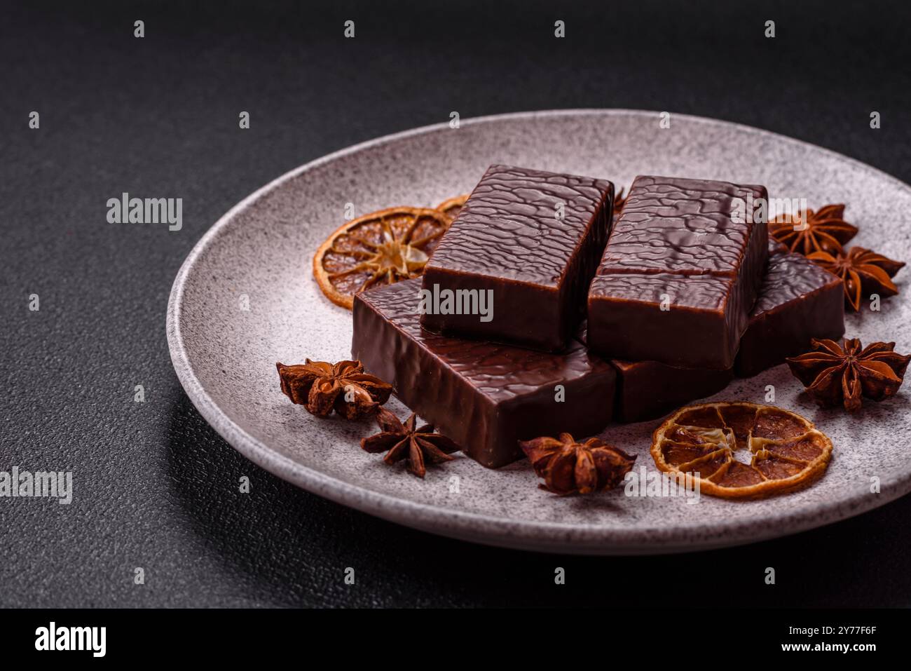 Rectangular chocolate candies with mousse and waffles on a dark ...