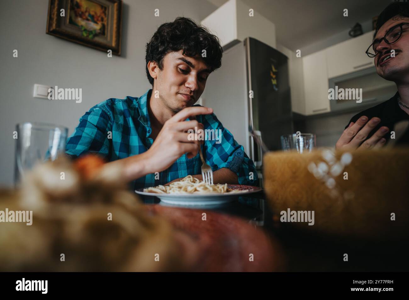 Friends enjoying pasta meal together at a cozy home setting Stock Photo ...