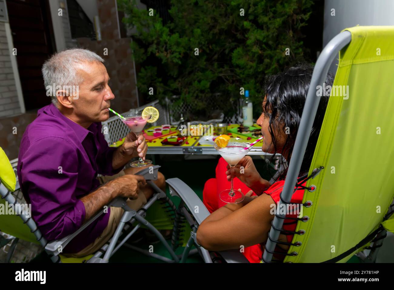 Happy romantic couple celebrating, holding glasses of cocktails with ...