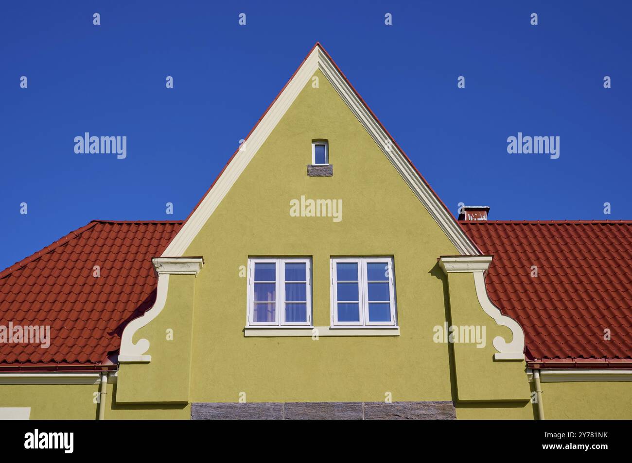 House gable with red tiled roof and white windows against a clear blue ...