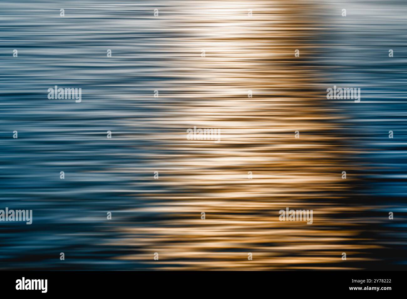 Golden sunlight reflecting on rippling water in a smooth, abstract ...